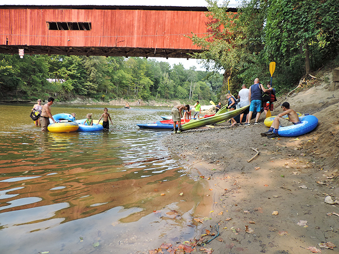 Summer fun flows beneath historic architecture as families make memories on Sugar Creek. The bridge has witnessed generations cooling off in these waters.