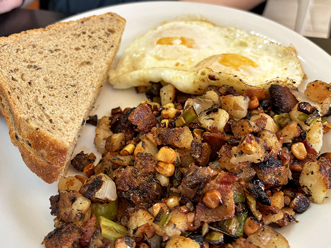 The breakfast holy trinity: perfectly fried eggs, crispy home fries with caramelized edges, and toast waiting patiently for its butter transformation.
