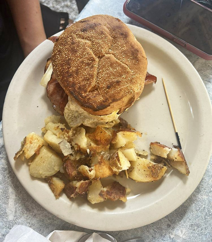 The breakfast sandwich arrives like a morning masterpiece &ndash; perfectly toasted bread cradling eggs and bacon with home fries that demand attention.