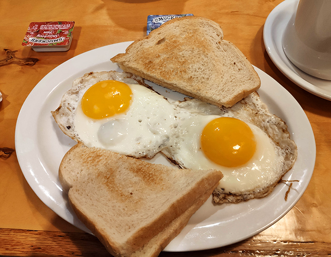 Two sunny-side up eggs with toast – breakfast simplicity that somehow tastes better when someone else makes it for you.