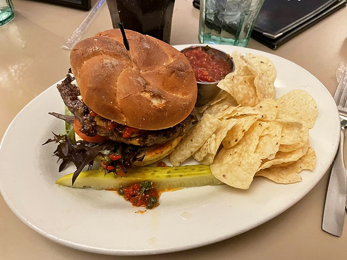 This isn't just a burger&mdash;it's architecture on a pretzel bun. The pickle spear standing at attention seems to salute its own deliciousness.
