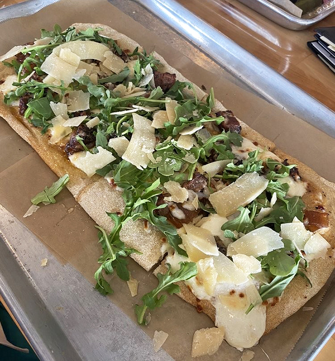 Flatbread that flirts with fine dining – arugula and shaved parmesan bringing sophistication to the smoky meat party underneath.