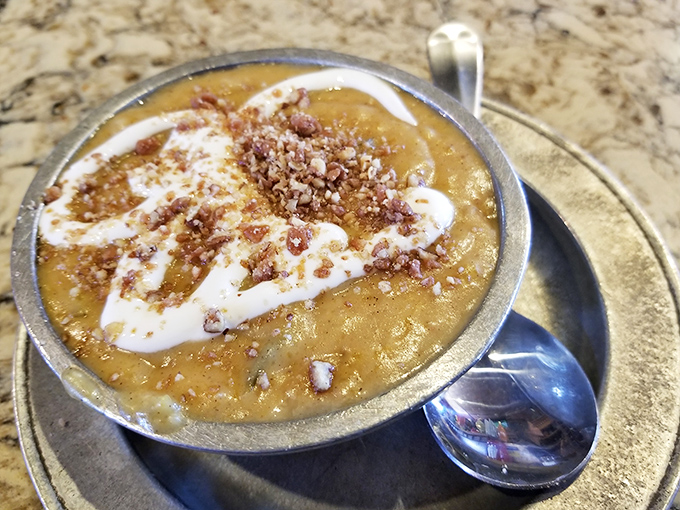 Butternut squash soup that wears its autumn colors proudly, topped with a swirl of cream and crunchy bits that add texture to every spoonful.