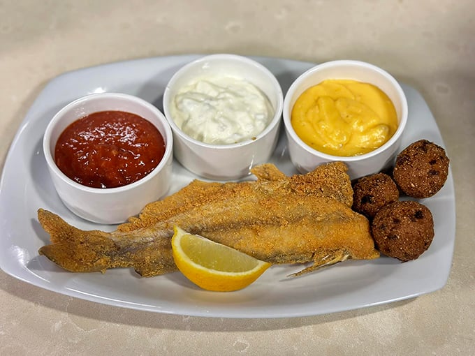The catfish arrives like a golden ambassador of the South, cornmeal-crusted and flanked by hushpuppies and three dipping sauces&mdash;because choices matter.