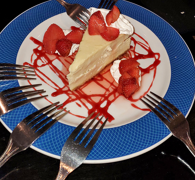 Cheesecake that makes you want to write poetry, surrounded by an artistic strawberry drizzle that would make Jackson Pollock jealous.