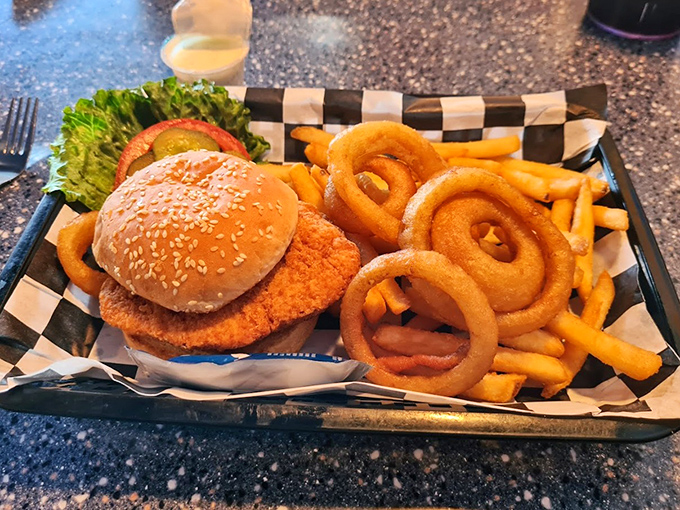 The chicken sandwich arrives with onion rings forming perfect orbital paths around it. Cosmic fast food that actually slows you down to savor.