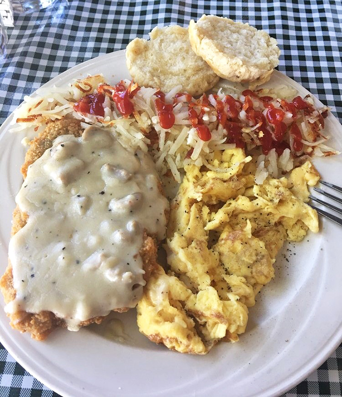 Country-fried steak wearing its gravy coat with pride, flanked by scrambled eggs that clearly never met a powdered mix in their lives.