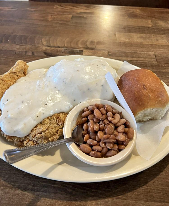 Southern comfort on a plate! This chicken fried steak smothered in peppery gravy alongside pintos and a fresh roll is what food dreams are made of.