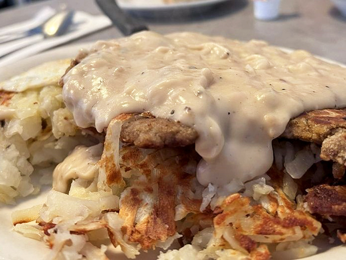 This isn't just gravy&mdash;it's liquid gold coating a perfectly prepared breakfast. The hash browns' crispy edges are the supporting actors in this delicious drama.