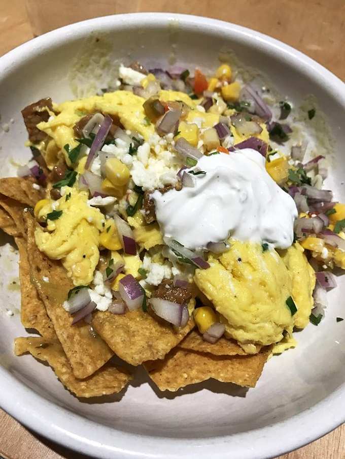 Tortilla chips playing dress-up with scrambled eggs, corn, red onion, and a dollop of sour cream&mdash;breakfast nachos that make mornings worth facing.