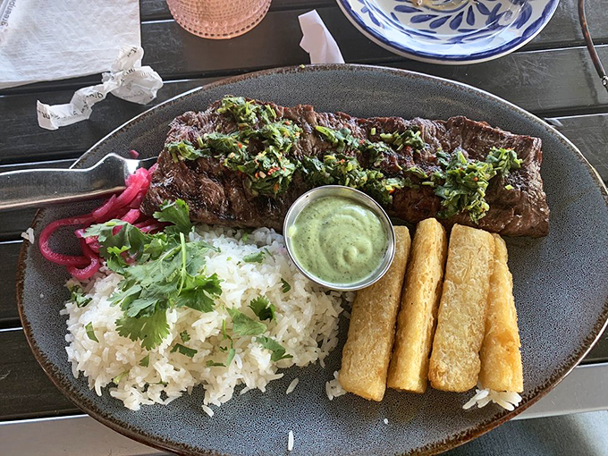Perfectly grilled steak crowned with chimichurri, served alongside cilantro rice and golden plantains&mdash;proof that simplicity and quality make magic on a plate.