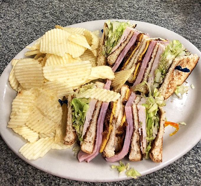 The club sandwich: architectural marvel of the lunch world. Stacked higher than your weekend expectations, with chips standing guard like crunchy sentinels.