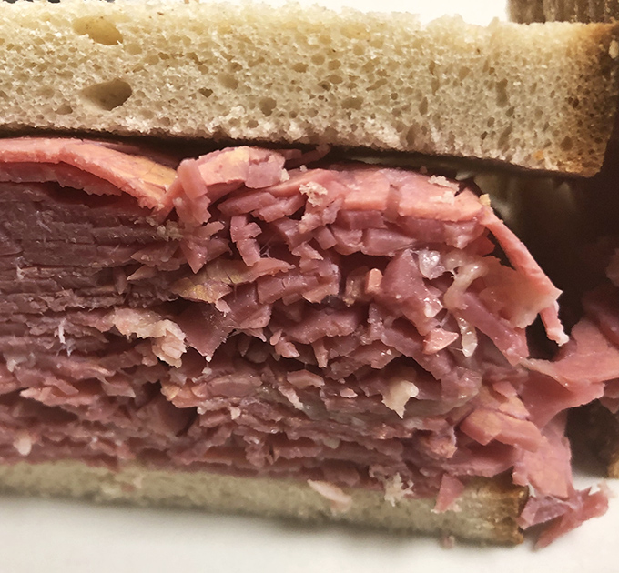 This sandwich isn't messing around – layers of corned beef stacked higher than your weekend plans, nestled between slices of fresh bread.