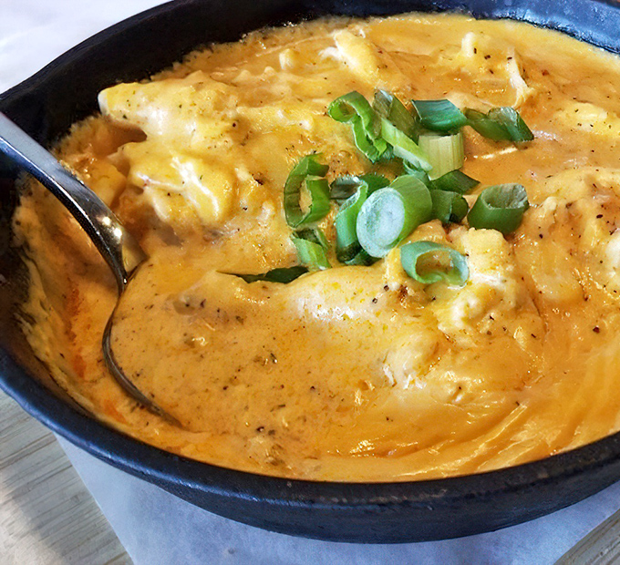 The crab dip arrives looking like a golden pool of decadence, with green onions adding both namesake nod and fresh contrast.