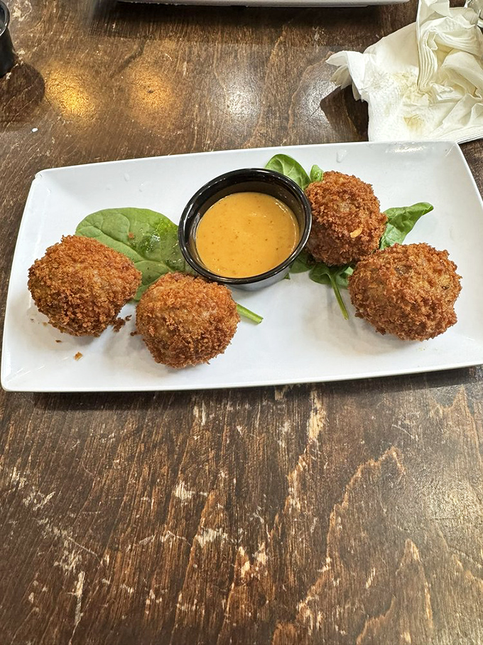 Golden-fried crawfish balls standing at attention, ready to dive into that creamy dipping sauce like eager swimmers.