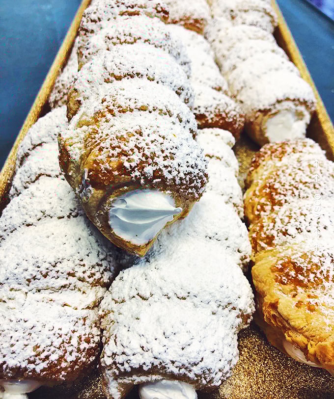 Cream horns dusted with powdered sugar like freshly fallen snow. One bite and you'll understand why people willingly wait in line.