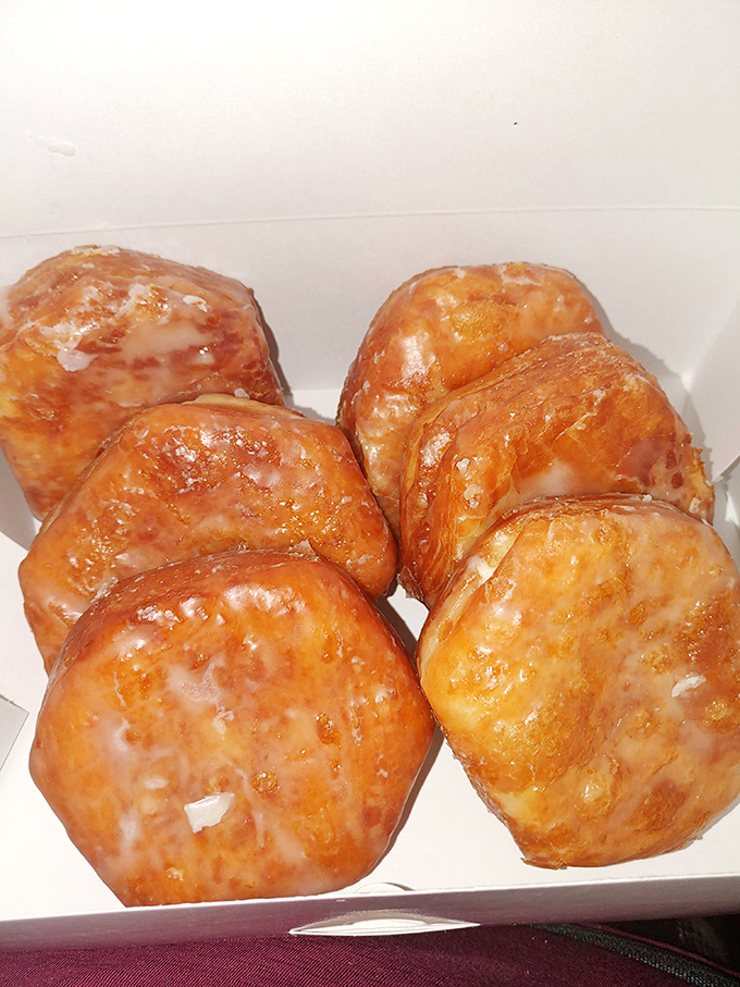 These golden-brown glazed donuts glisten under the lights, their perfect sheen promising that satisfying first bite crackle we all live for.