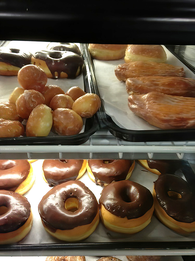 Chocolate-glazed donuts lined up like soldiers, ready to sacrifice themselves for your morning coffee ritual.
