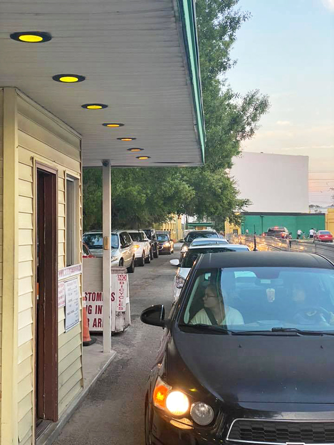 Yellow lights guide moviegoers to their evening escape, the theater's entrance a gateway to two hours of worry-free entertainment.