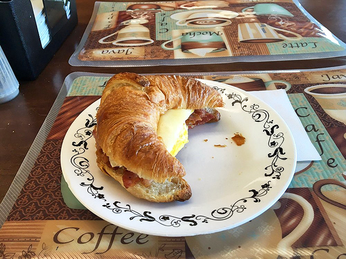 The croissant sandwich, half-eaten because waiting to photograph it intact requires superhuman restraint that most mortals simply don't possess.
