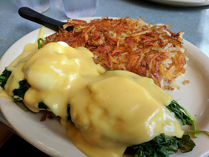 Eggs Benedict done right: golden hollandaise cascading over perfectly poached eggs, with those legendary hashbrowns standing by for backup.