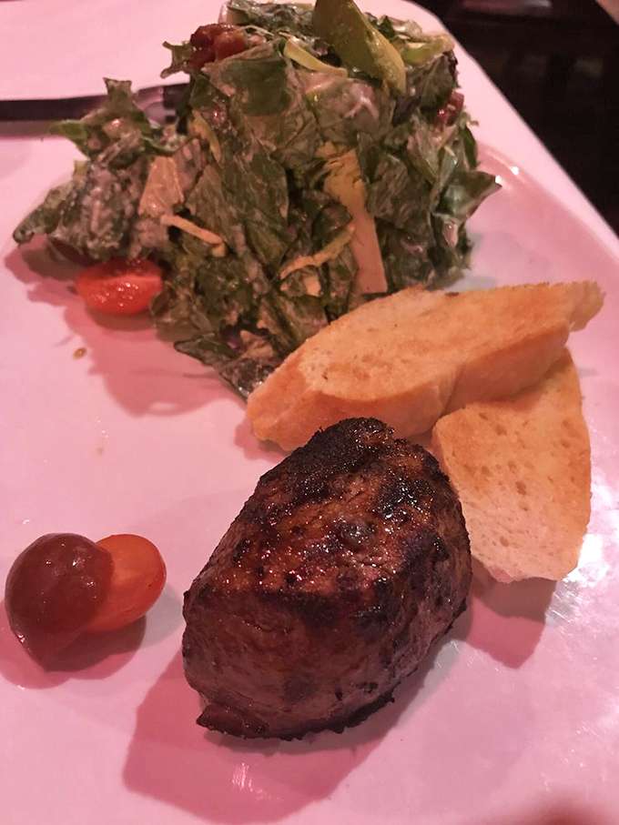 The filet mignon sits like royalty on the plate, surrounded by its loyal subjects: fresh greens, toasted bread, and a cherry tomato crown jewel.