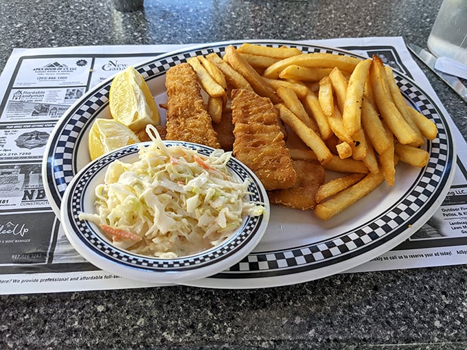 Golden fish fillets that crackle with each bite, nestled beside fries that could convert a potato skeptic. That coleslaw? Pure creamy contrast.