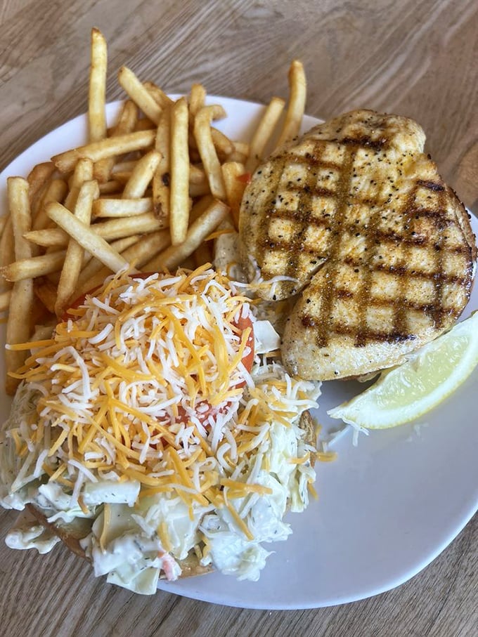 A perfectly grilled fish fillet perched atop coleslaw like it's surveying its french fry kingdom before being devoured.