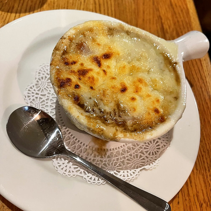 French onion soup done right&mdash;a bubbling cauldron of sweet onions beneath a golden cathedral ceiling of melted cheese. Spoon-breaking perfection.