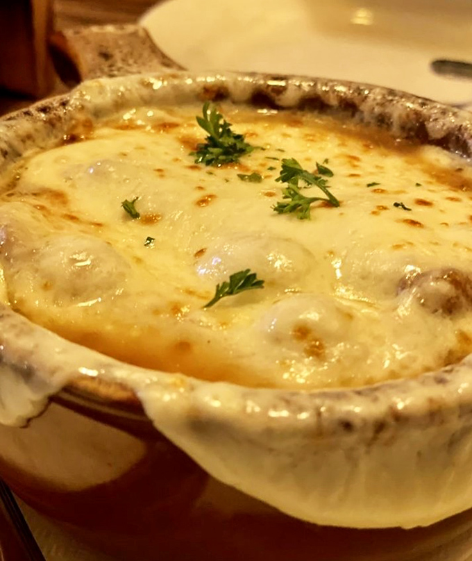 French onion soup that's achieved the golden trifecta: perfectly caramelized onions, rich broth, and a cheese cap that stretches like a gymnast going for gold.