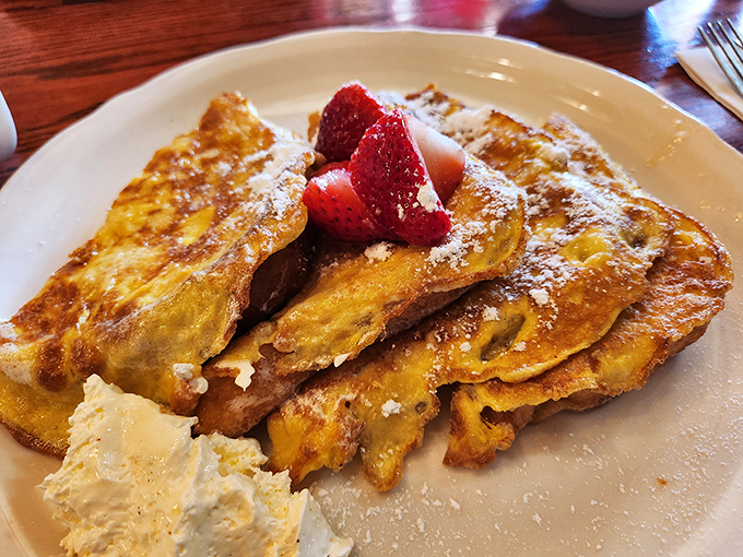 French toast that makes ordinary bread weep with jealousy, topped with fresh strawberries and a cloud of whipped cream worth every calorie.