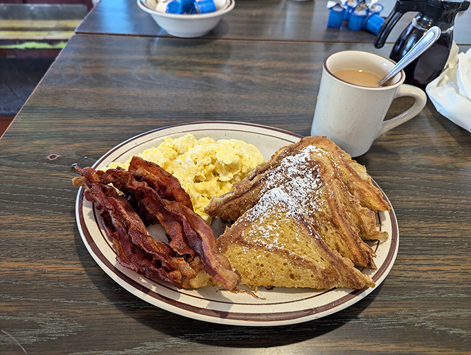 The breakfast trinity: perfectly crisp bacon, fluffy scrambled eggs, and French toast dusted with powdered sugar like a light LA morning fog.