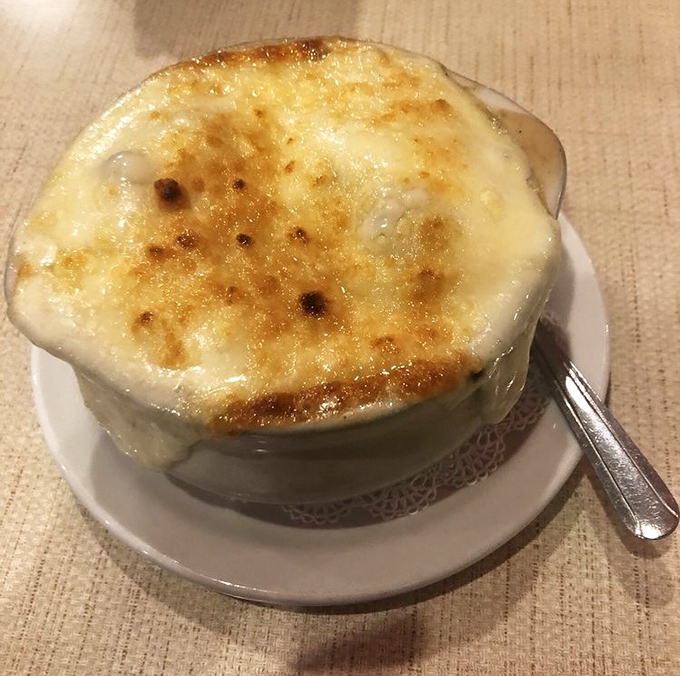 French onion soup that's wearing its cheese like a winter coat. That golden, bubbling crust is practically begging for a dramatic spoon break.