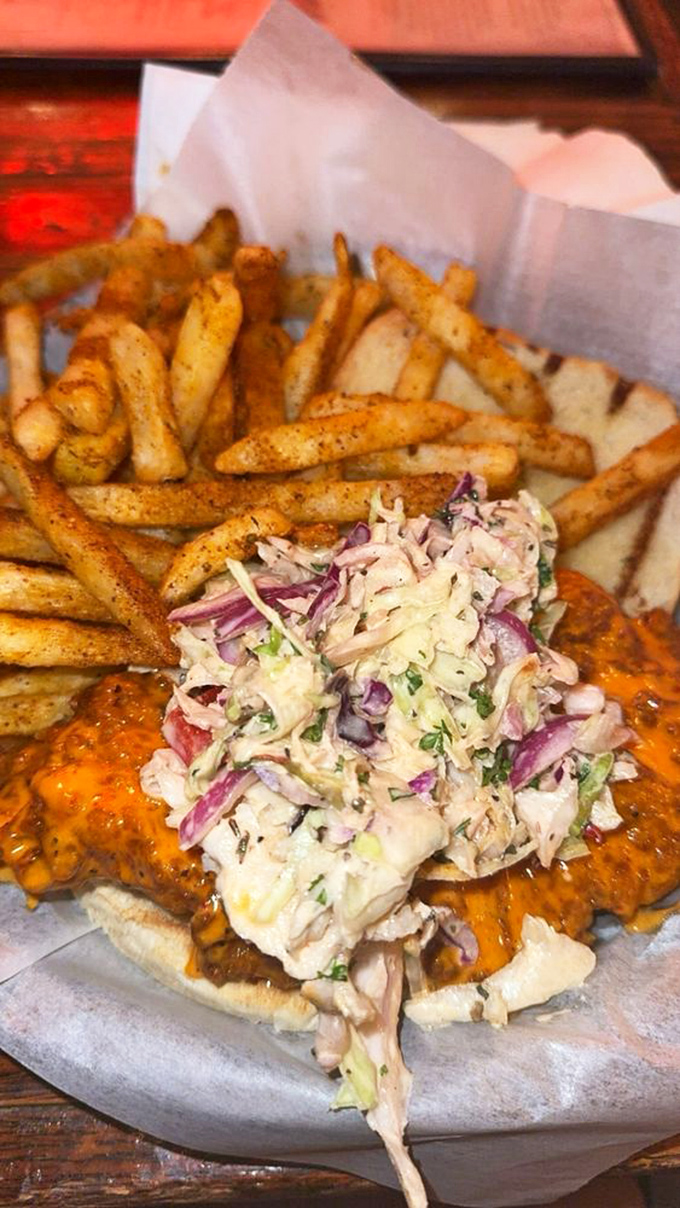 The ultimate comfort food trifecta: spicy Cajun fries, creamy coleslaw, and a sandwich that requires both hands and several napkins.