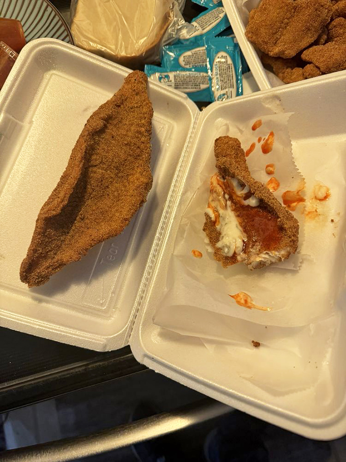 The perfect fried fish reveals itself in cross-section: crispy, golden exterior giving way to flaky, tender fish. This is seafood architecture at its finest.