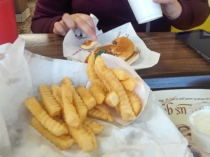Crinkle-cut fries that snap with each bite, nestled beside a burger that's seen more presidential administrations than most employees. Comfort food democracy in action.