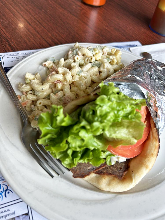 A gyro wrap that requires both hands and a strategy—crisp lettuce, fresh tomato, and hearty fillings served with creamy pasta salad.
