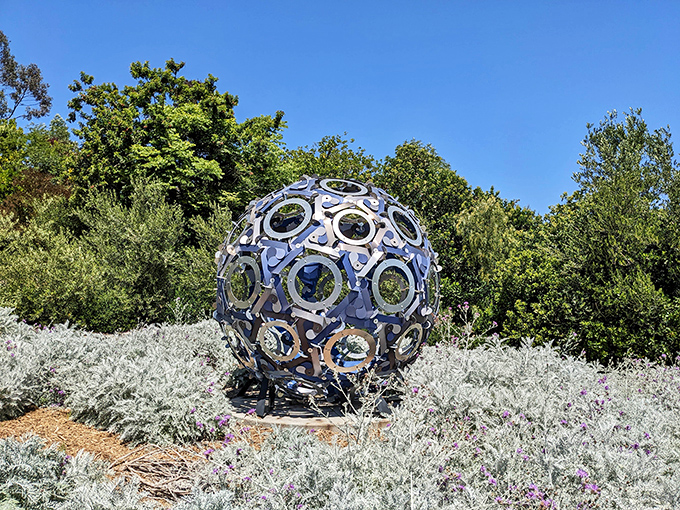 This mesmerizing metal sphere sculpture plays hide-and-seek with sunlight, creating ever-changing patterns across the garden floor.