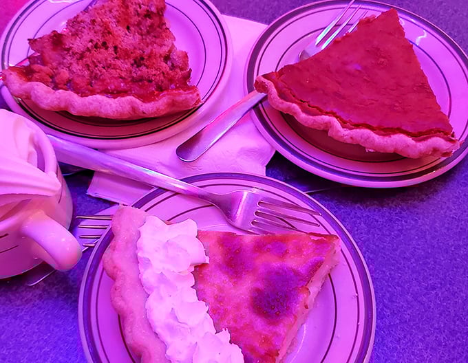 Three slices of homemade pie bathed in the diner's signature pink glow &ndash; proof that sometimes the best things in life come in triangular form with whipped cream on the side.