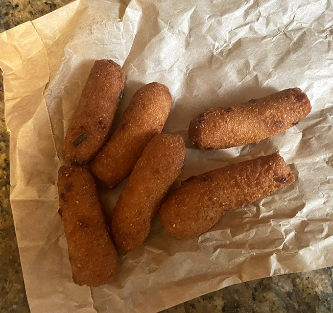 Crispy hush puppies lined up like golden soldiers, ready to soak up sauce and disappear faster than common sense.