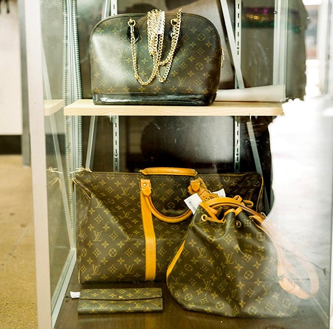 Designer dreams within reach! Louis Vuitton bags displayed behind glass&mdash;the thrift store equivalent of finding a unicorn in your backyard.