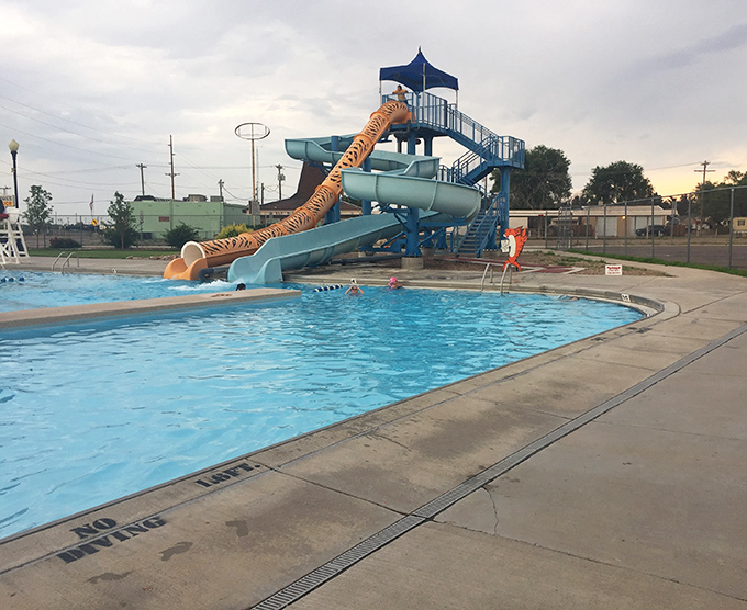 Nothing says "summer in small-town America" quite like a community pool with a slide that promises just enough thrill without requiring a signed waiver.