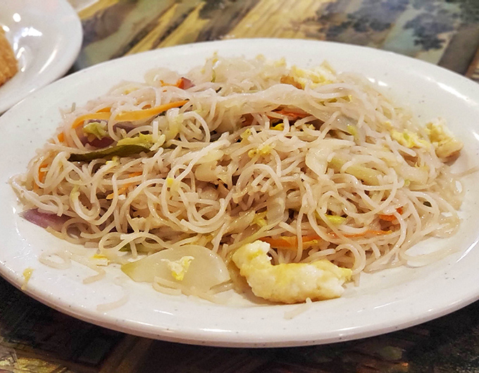Delicate strands of lo mein intertwine with colorful vegetables and bits of egg—a simple dish elevated to art form through perfect texture and balance.