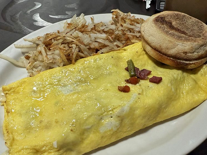 This isn't just an omelet; it's a golden envelope delivering a message of breakfast perfection, with hash browns that look like they've been practicing their crispiness for years.