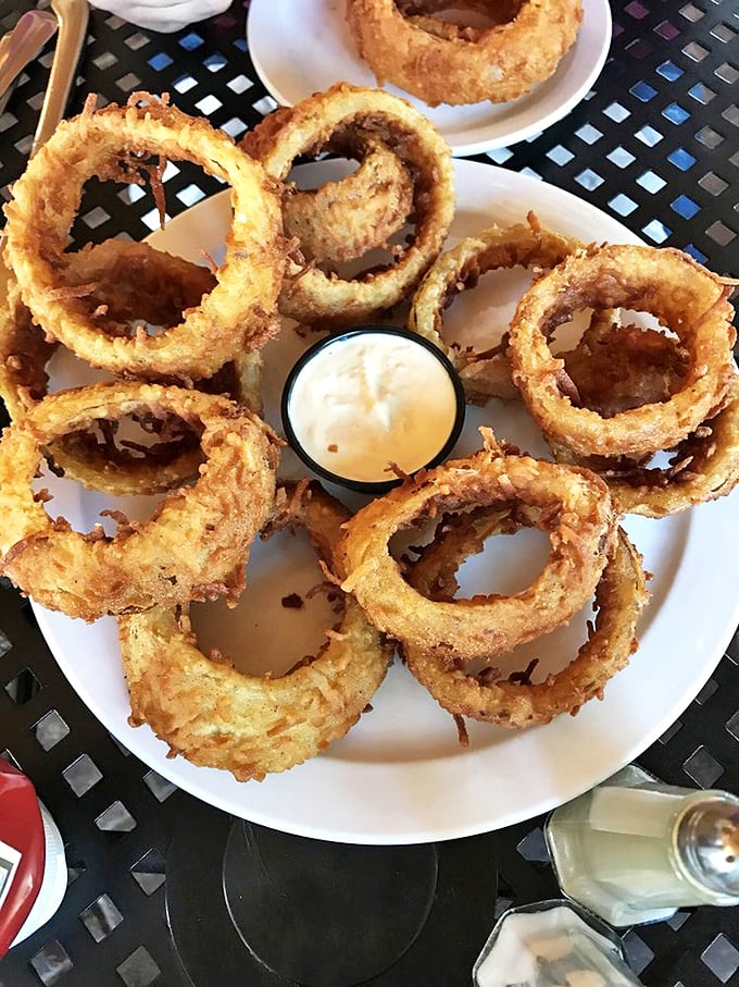 Golden onion rings stacked like delicious halos, with dipping sauce standing by for its supporting role in this crispy drama.