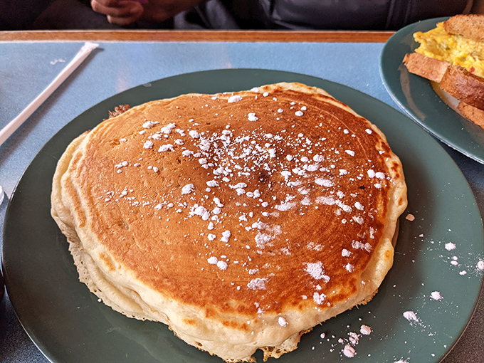 Not just a pancake, but a fluffy canvas of possibility dusted with powdered sugar, waiting for its maple syrup baptism.