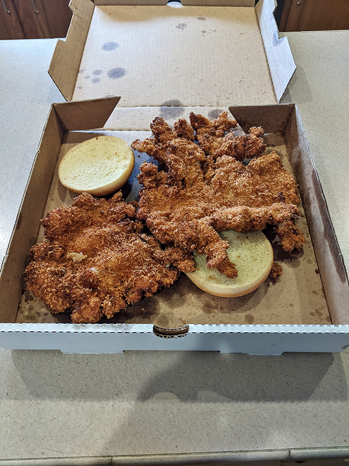 Two buns trying their best to contain the impossible – a tenderloin that's been pounded thin, breaded thick, and fried to crispy perfection.