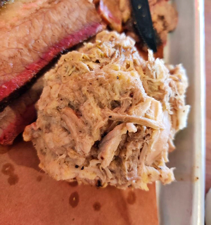 Pulled pork so tender it practically surrenders at the sight of your fork, nestled beside a slice of brisket that's wearing its smoke ring like a badge of honor.