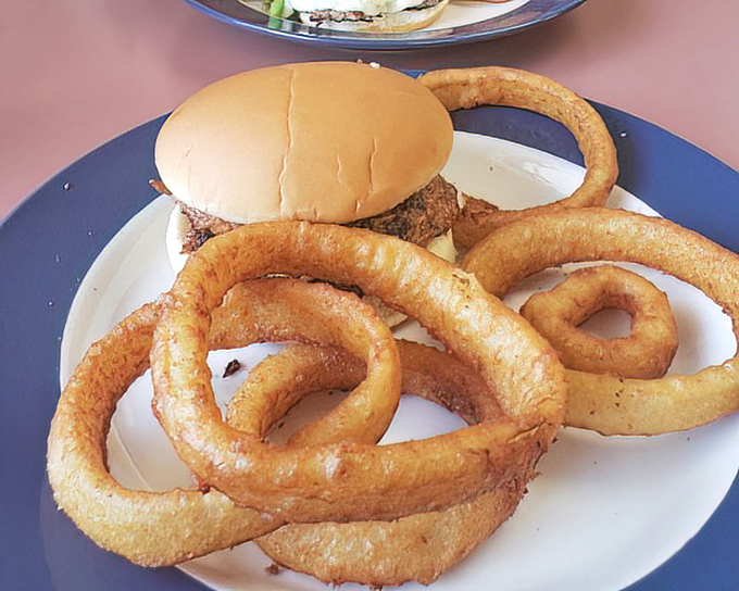 Onion rings the size of bracelets surrounding a sandwich that doesn't need fancy aioli to make its point. This is honest food speaking its truth.