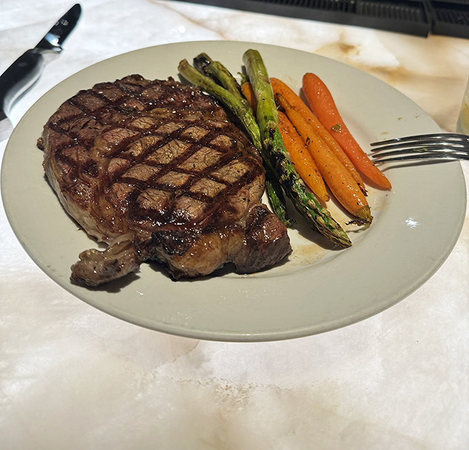 This ribeye's perfect grill marks aren't just for show &ndash; they're a roadmap to flavor country, with au jus that deserves its own fan club.